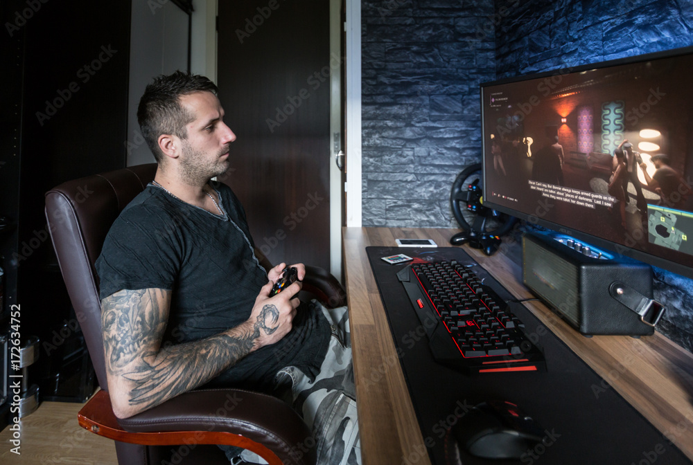 Gaming room.Young man playing video games on computer with joystick in ...