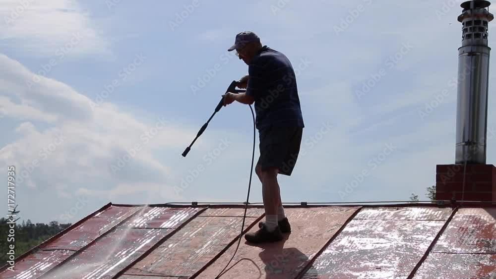 Man is washing the roof with a high pressure washer. Contrast ...