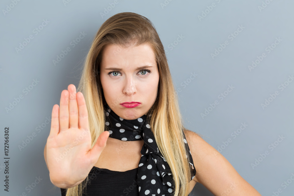 Young woman making a rejection pose on a gray background Stock-Foto ...