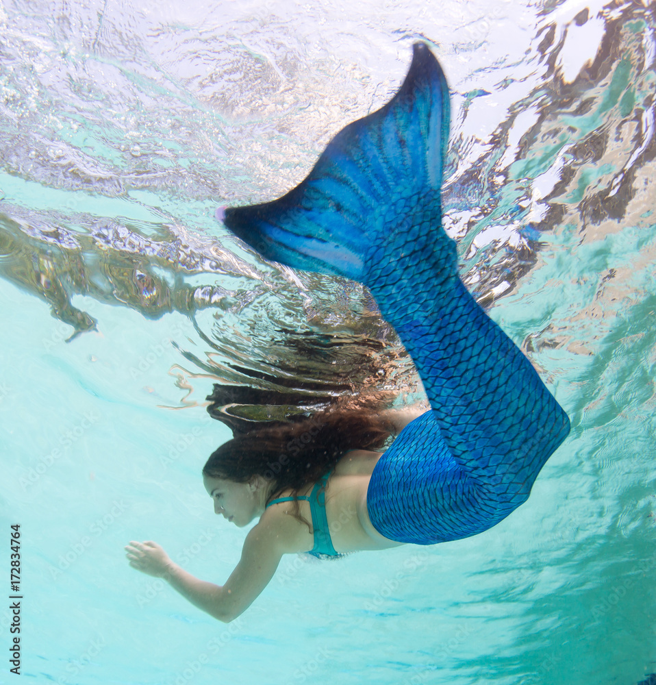 Model in a pool wearing a mermaid's tail. Stock Photo | Adobe Stock