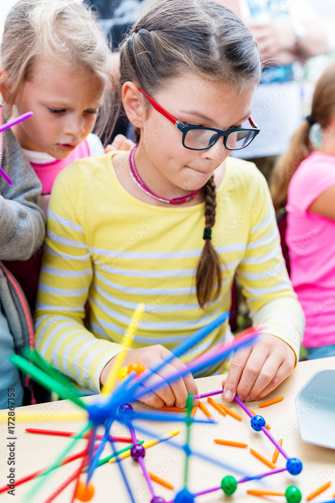 Two little girls playing with lots of colorful plastic sticks kit ...