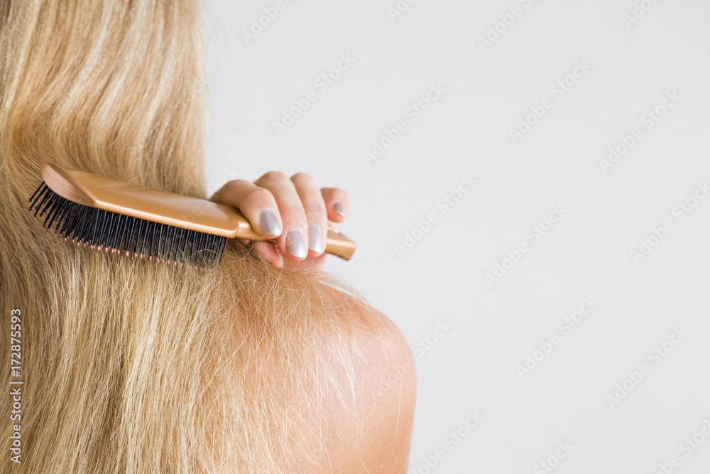 Woman's hand brushing blonde hair. Cares about a healthy and clean hair ...