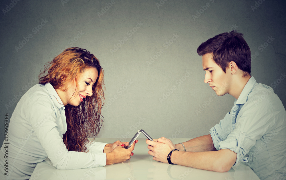 Smartphone addiction concept. Woman and man sitting at table with smart ...