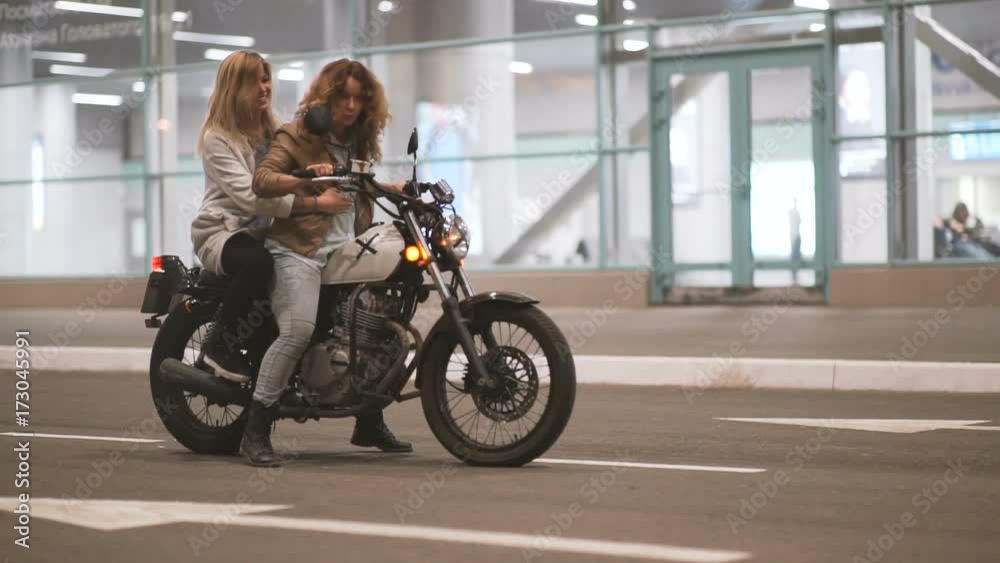 Two beautiful young women riding a motorcycle at night on city street ...