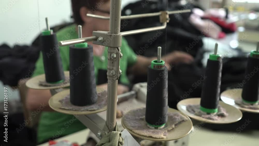 Sewing machine pulling threads of spools in focus, professional female ...