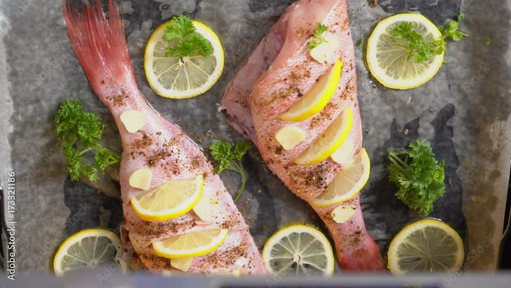 Cooking whole roasted fish with lemon and herbs baked in the oven. View ...