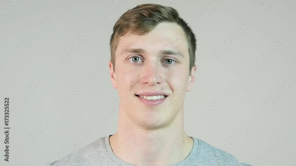 Young man winking, isolated on white background. Close up of a happy ...
