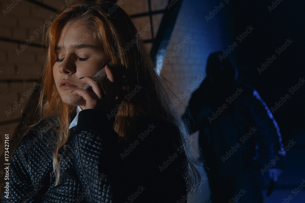Foto de Criminal stalking a girl alone in a dark street. He is hiding ...
