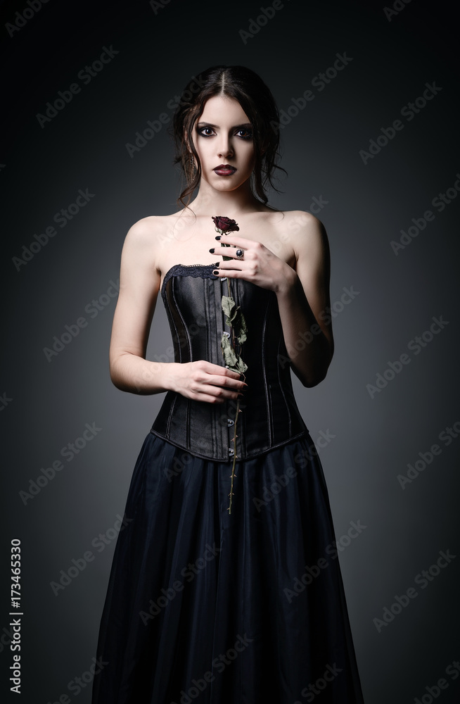 Foto Stock Portrait of beautiful goth girl holding withered rose in ...