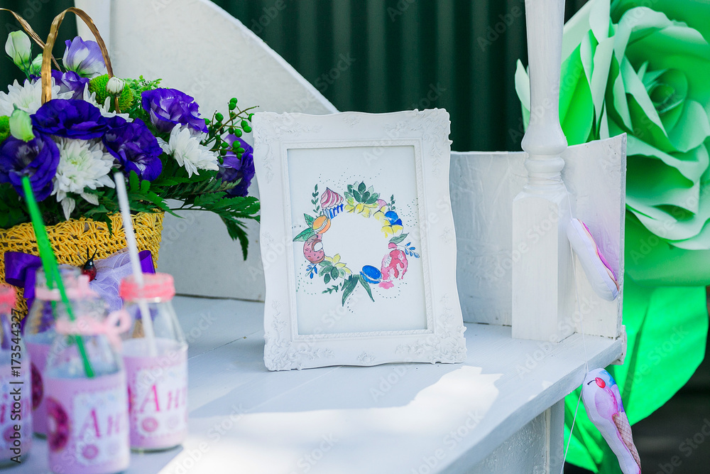 A glass bottles on a kandi bar. frame on the table with flowers and ...