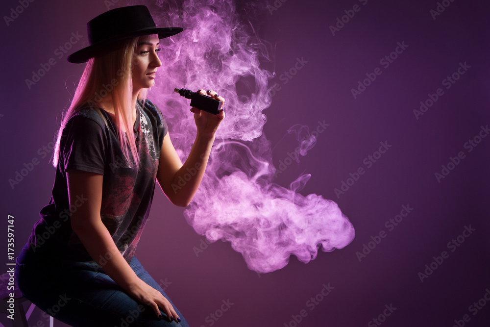 Foto de Smiling female model smoking fruit flavored e-liquid or e-juice ...