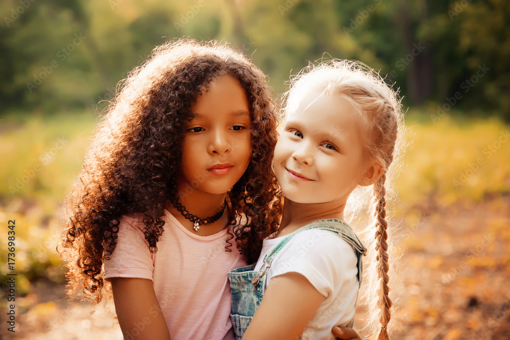 Two happy girls as friends hug each other in cheerful way. Little ...