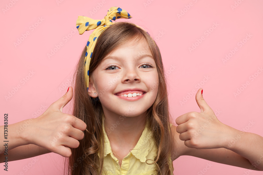 Smiling girl holding thumbs up Stock Photo | Adobe Stock
