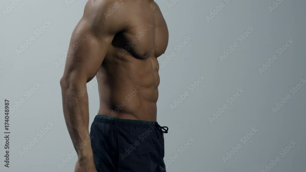 A fitness model flexes his arms in a stretch displaying his pectorals ...