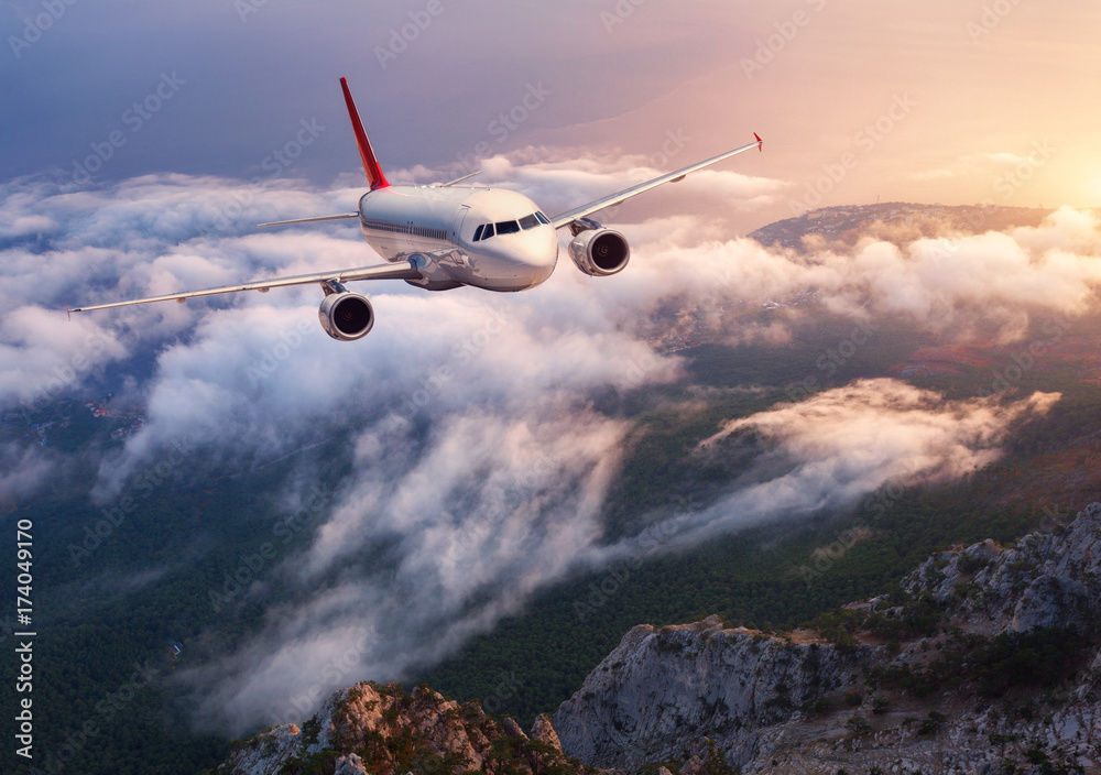 Beautiful airplane is flying over low clouds at sunset. Landscape with ...