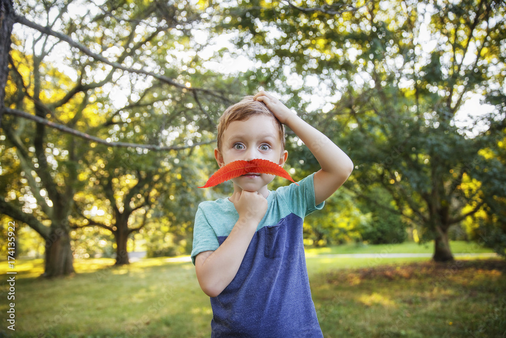 cute little boy wearing bright red mustache from autumn leaves. funny ...