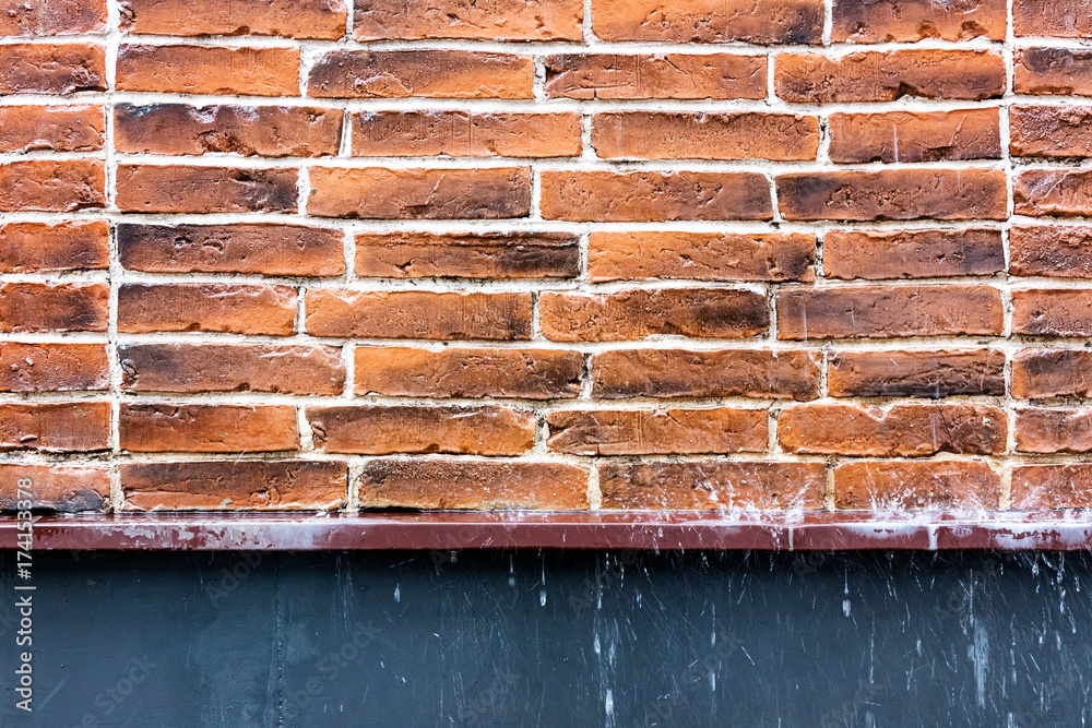 heavy rain in the city. surface of red brick wall with raindrops ...