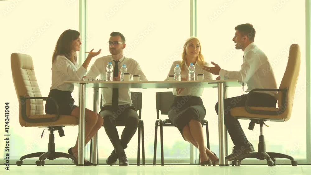 The four business people sit at the office table near the panoramic ...