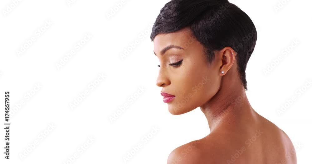 Close up of gorgeous black female with bare shoulders looking down on ...