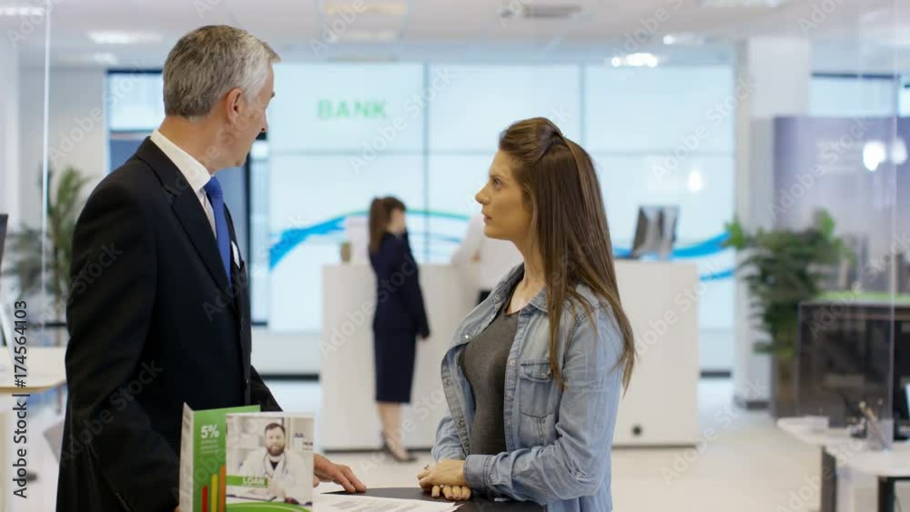 Bank worker on information desk giving help & advice to customers Stock ...