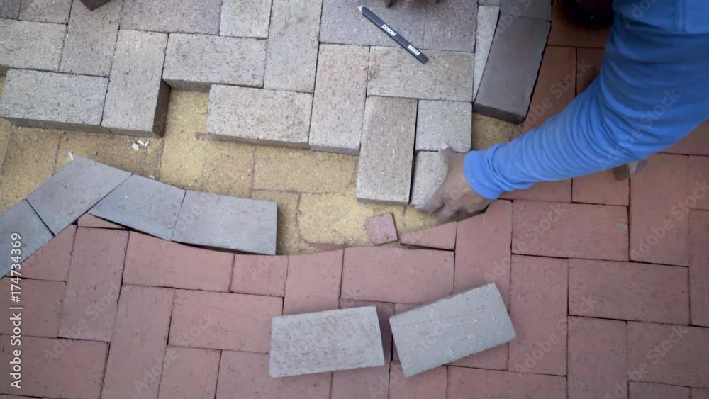 Camera overhead focussing on stone cutter fitting a cut brick into ...