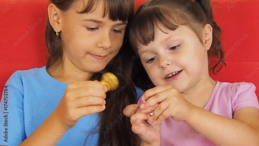 Little girls are playing with a spinner. Happy little sisters twist the ...