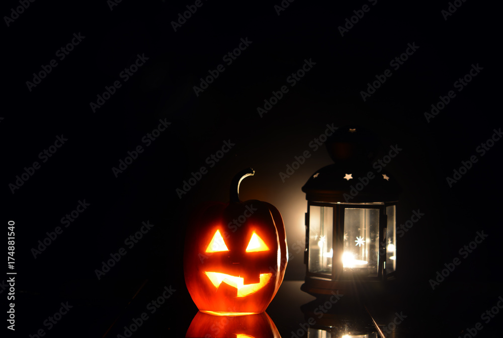 Тыква с вырезанными глазками и ртом, со свечой внутри, на темном фоне ...