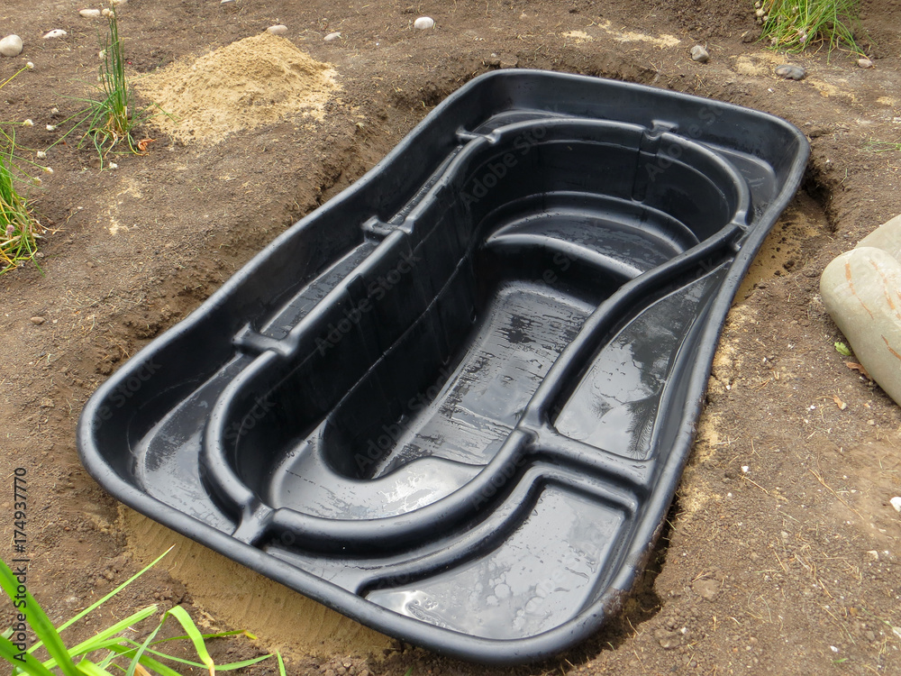Preformed plastic pond insert installation in a dug stepped hole with ...