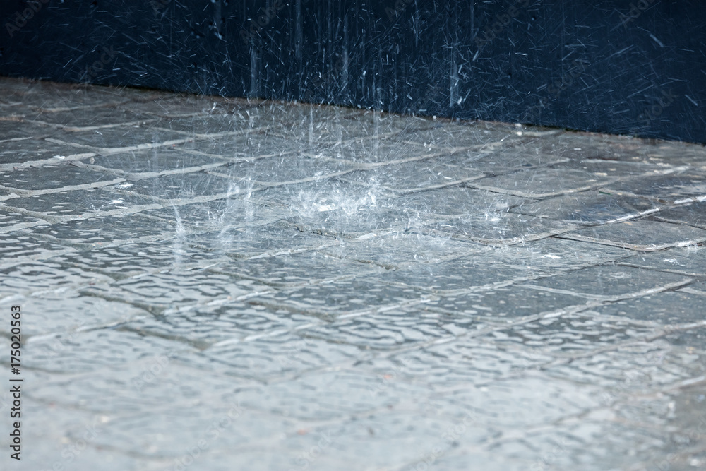 heavy raindrops falling on pavement. surface of cobblestone sidewalk ...