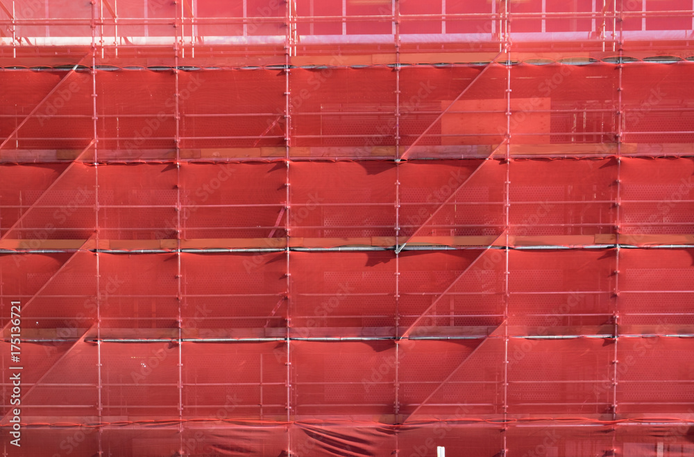 scaffolding on a building construction site covered with red safety ...