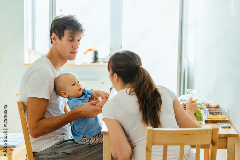 Real people scene: young happy family having breakfast together. Infant ...