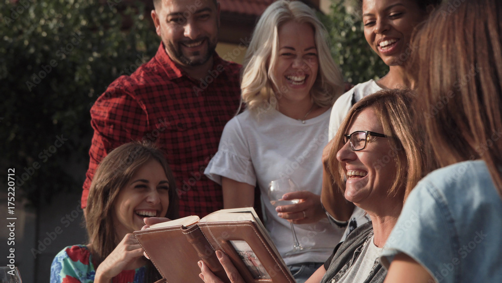 Smiling family standing together while watching photos in album. Stock ...