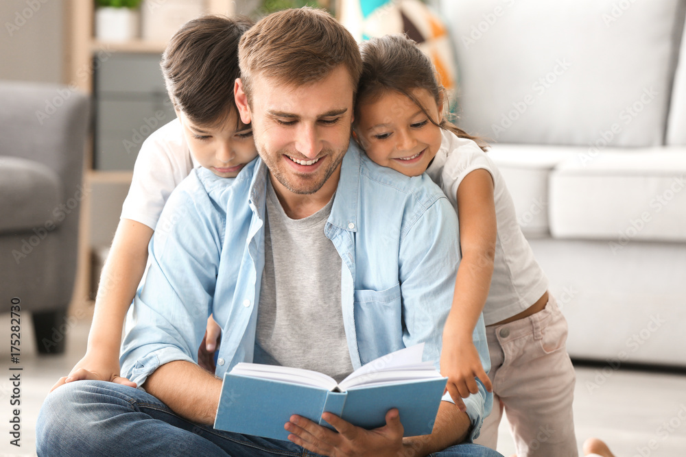 Young man and his little children reading book at home Stock-Foto ...