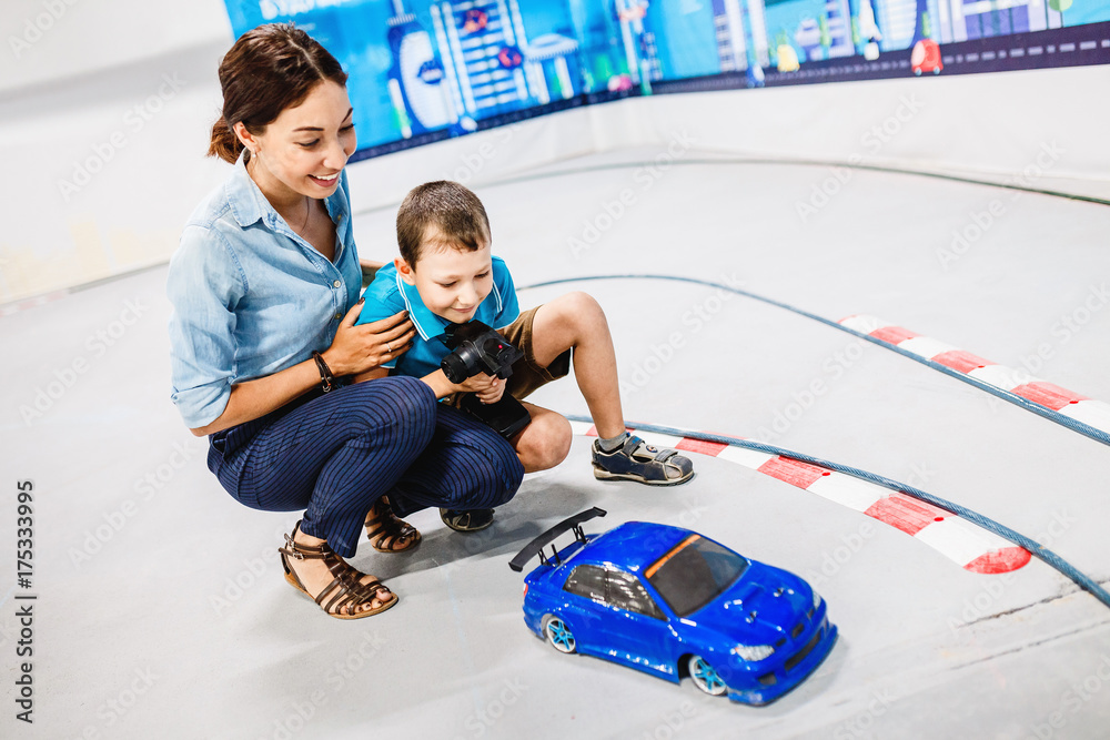 Little boy with his mother playing with radio remote controlled car at ...