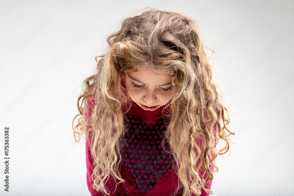 Sad curly-haired schoolgirl with head down Stock Photo | Adobe Stock