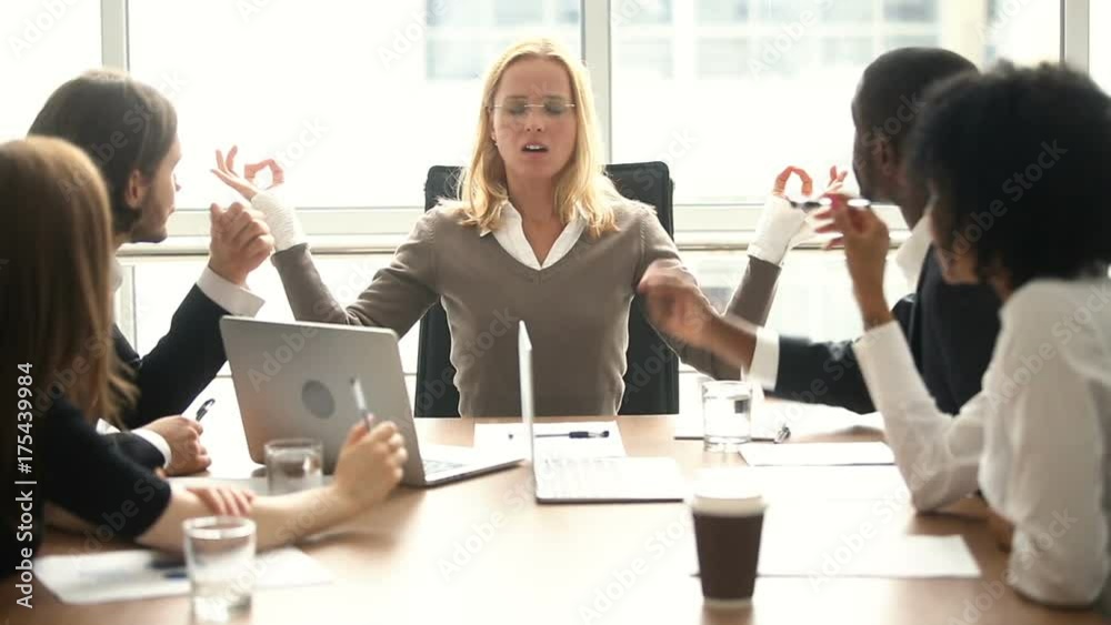 Calm young businesswoman meditating with eyes closed at meeting with ...
