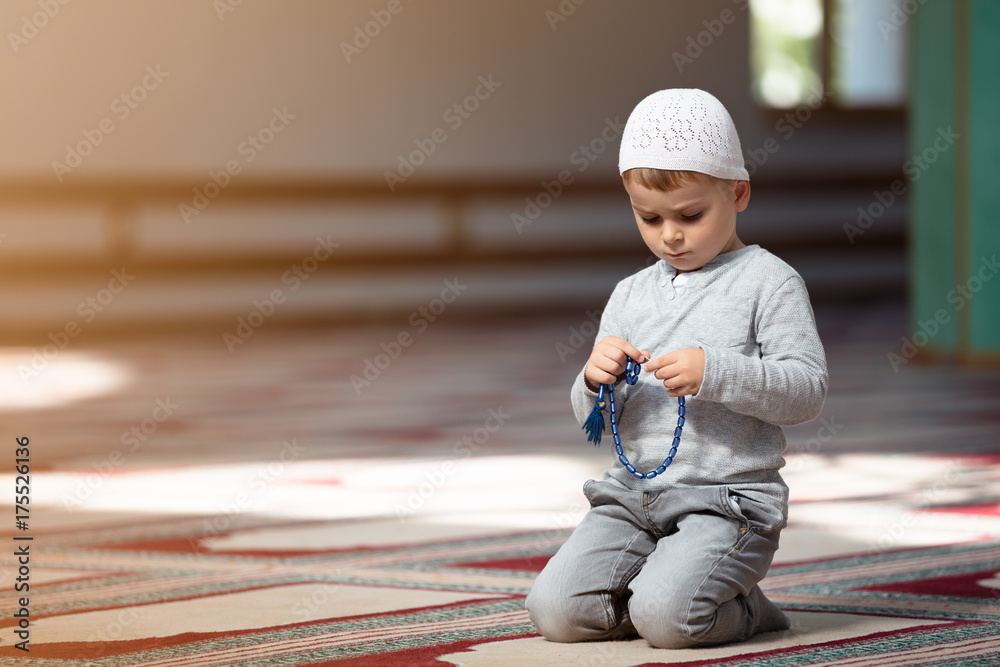 The Muslim child prays in the mosque, the little boy prays to God ...