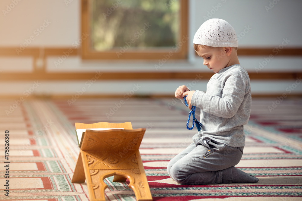 The Muslim child prays in the mosque, the little boy prays to God ...