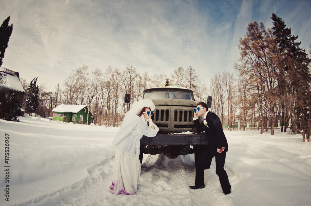 The beautiful ginger bride in a white fur coat and a groom in colored ...