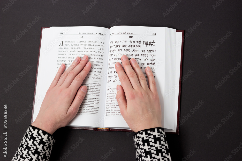 Jewish book, with woman's hand, on black background. Text of the Hebrew ...