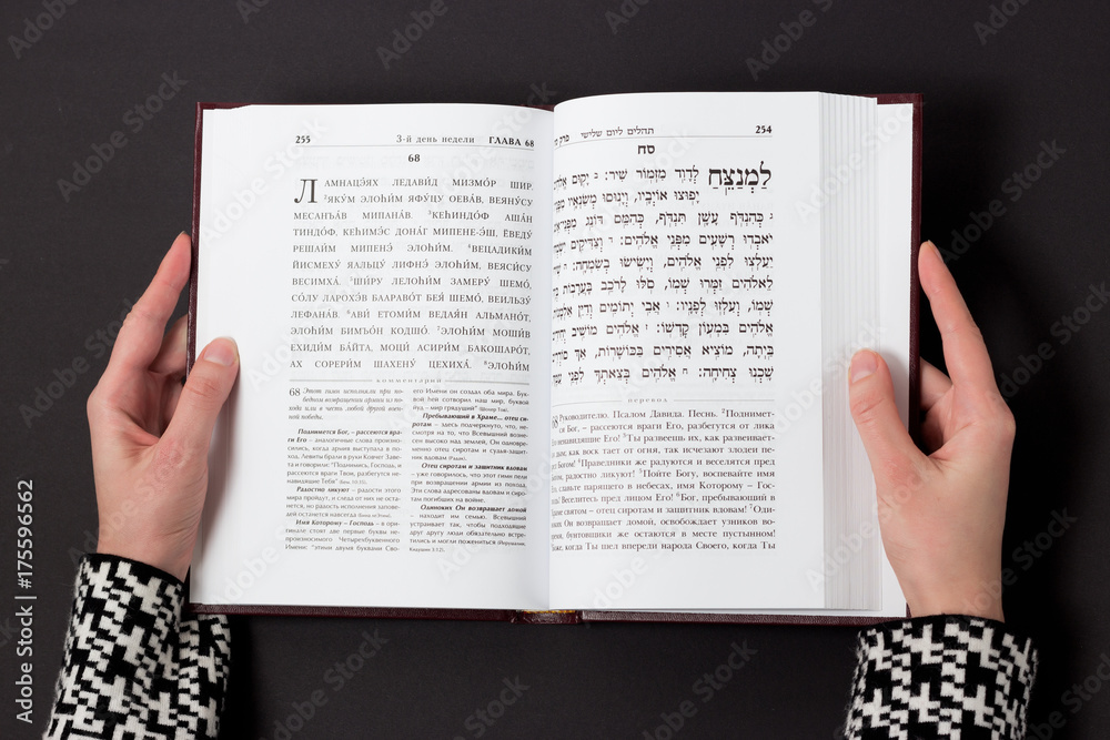 Jewish book, with woman's hand, on black background. Text of the Hebrew ...