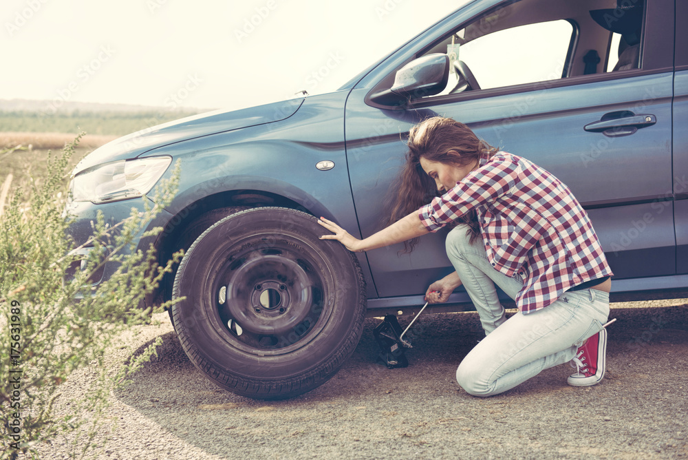 .Beautiful young woman changing tires on her car Stock Photo | Adobe Stock