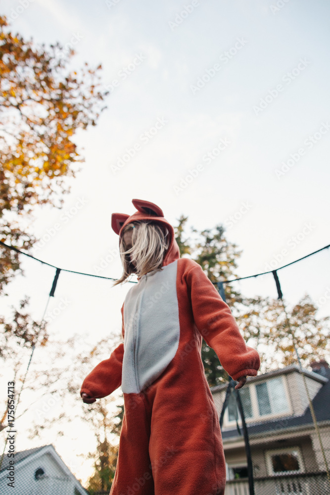 Cute girl in fox costume jumping on trampoline Stock Photo | Adobe Stock