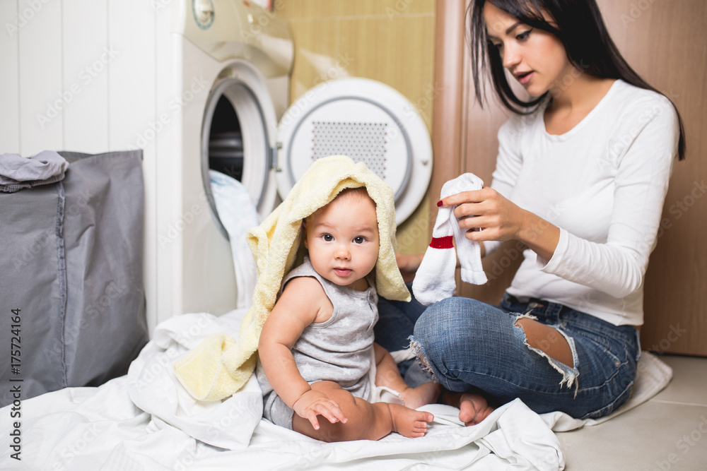 Mother and cute baby boy loading clothes into washing machine. Stock ...