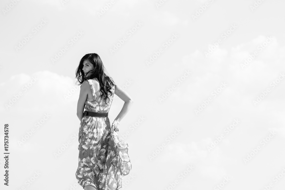 Pretty woman dressed in summer long light colorful dress posing on sand ...