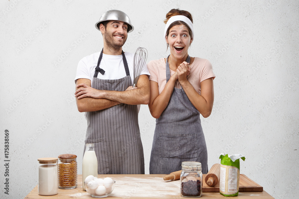 Astonished overjoyed female in apron looks with bugged eyes and ...