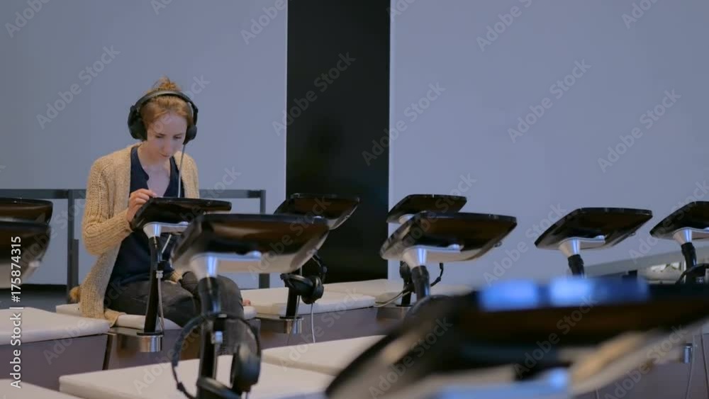 Woman using interactive touchscreen display and listening audio guide ...