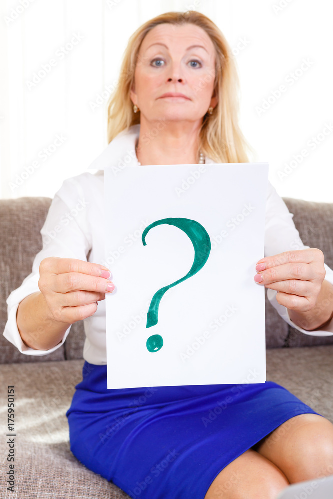 Old senior woman sitting on the sofa and holding a sheet of paper with ...