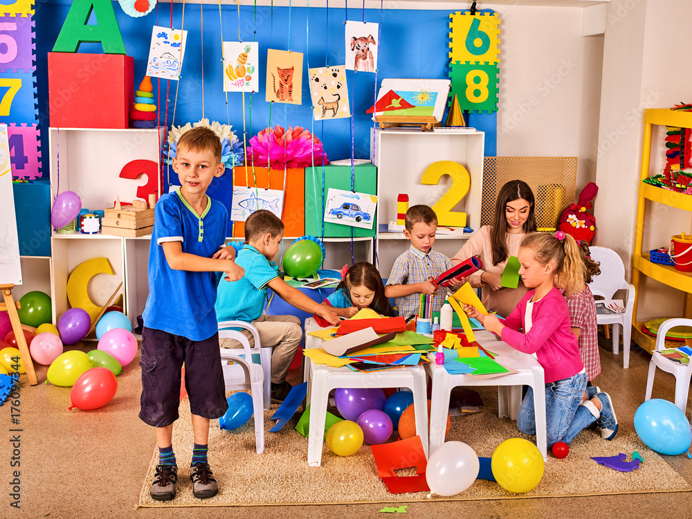 School children with scissors in kids hands cutting paper with teacher ...