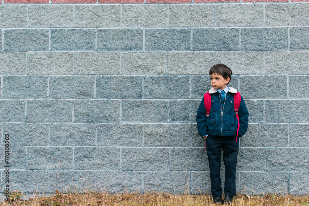 Boy standing alone outside school building Stock Photo | Adobe Stock